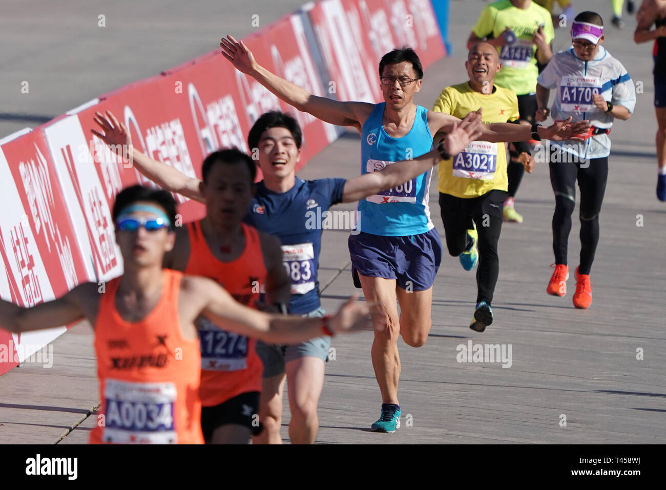Beijing, China. 14th Apr, 2019. Participants cross the finish line ...