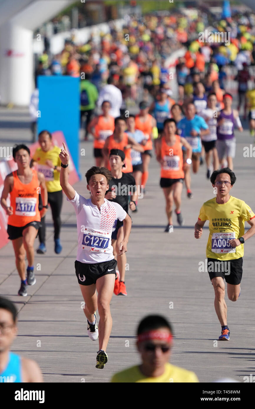 Beijing, China. 14th Apr, 2019. Participants cross the finish line ...