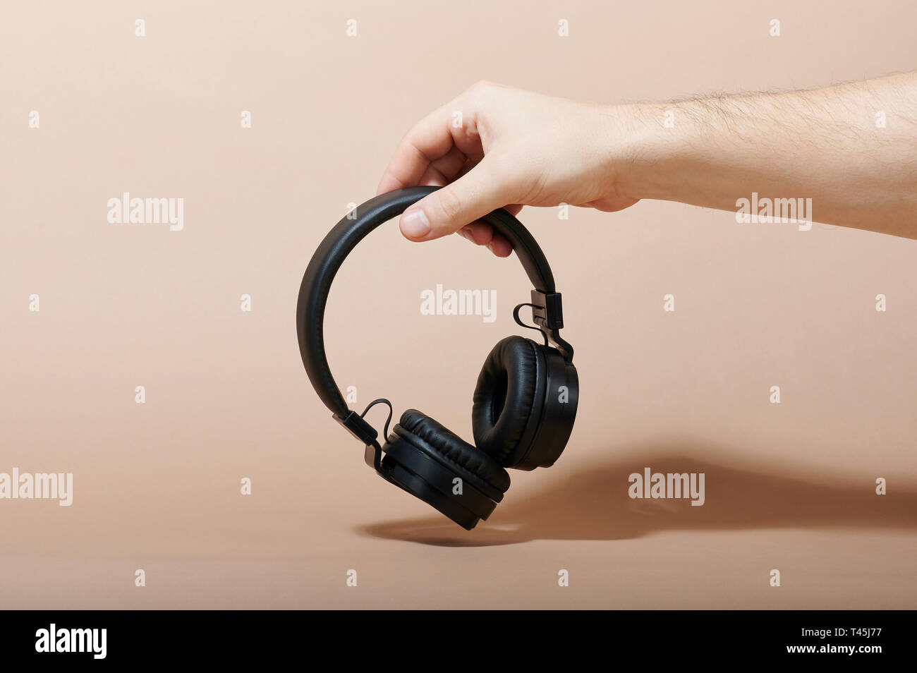 Man hand hold black headphones on beige color background Stock Photo ...