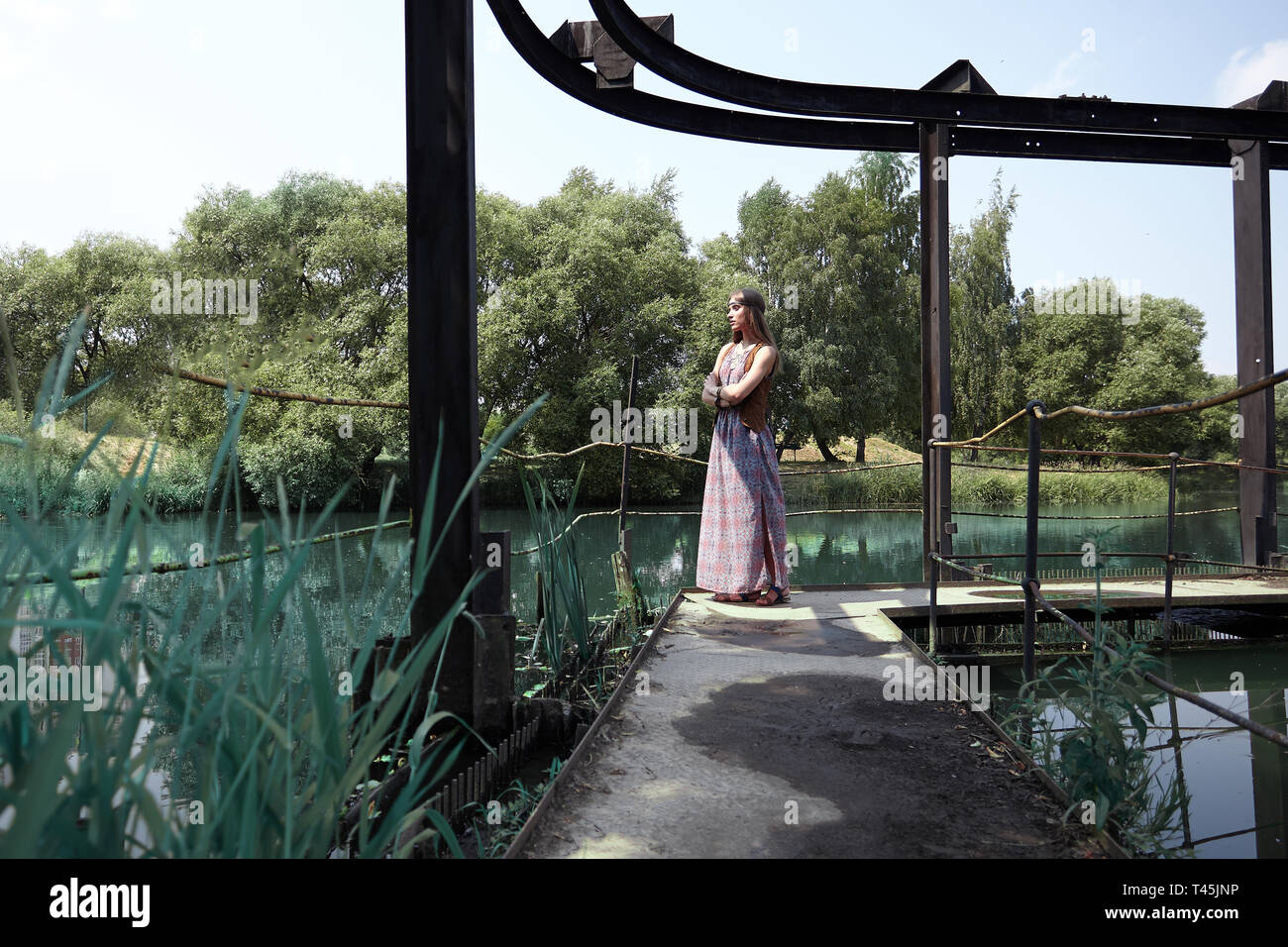 young hippie woman standing on wooden bridge on summer day. the concept ...