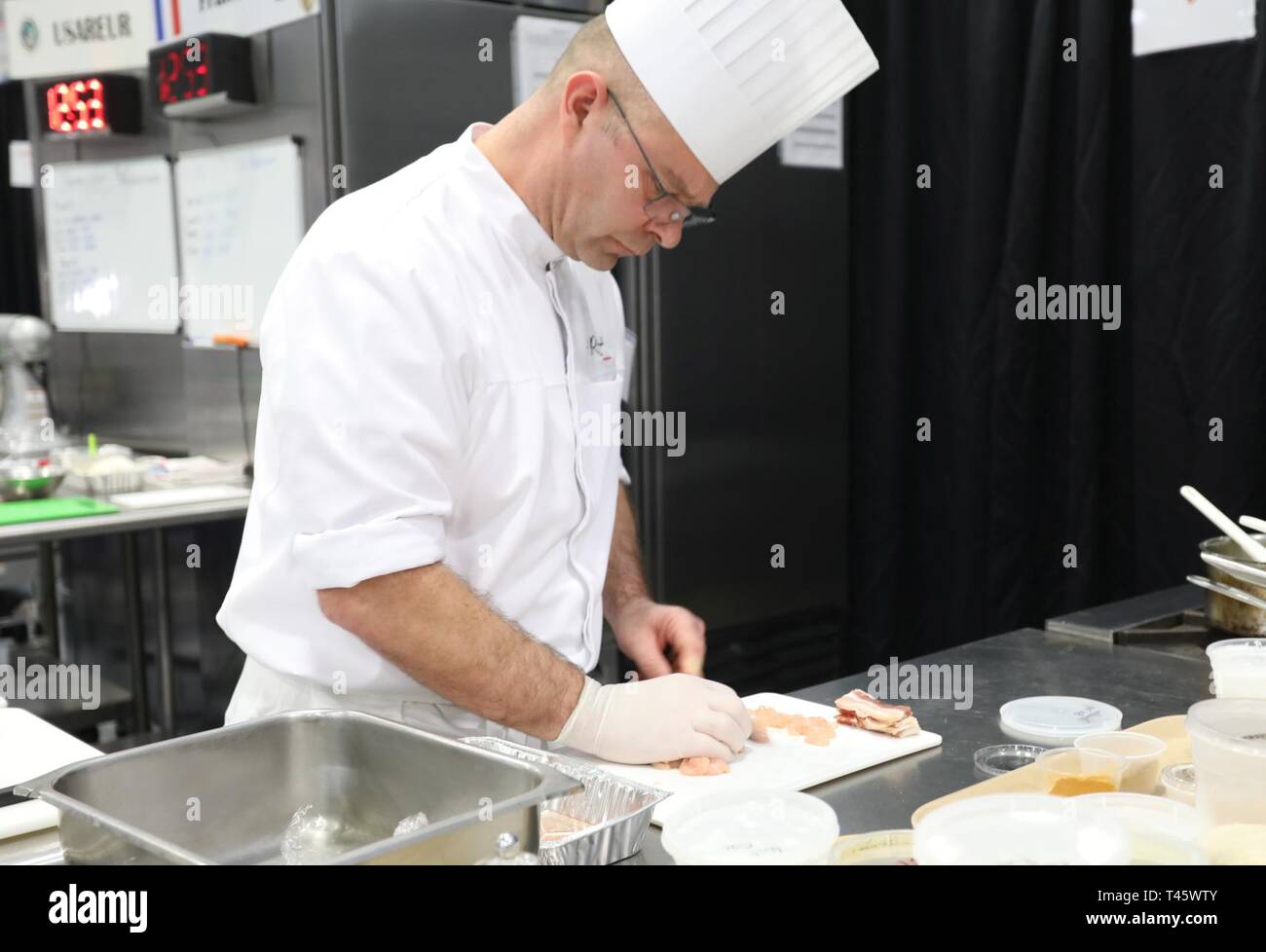 Lt. Col. Thierry Roussel, French miliary chef, cuts chicken during the ...