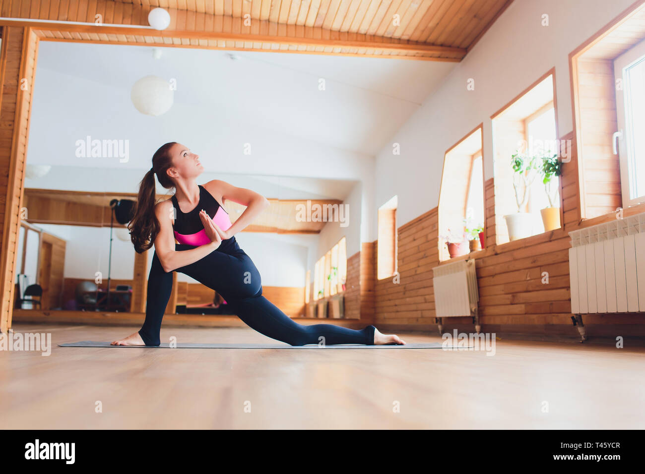 Young attractive yogi woman practicing yoga, standing in Parivrtta ...