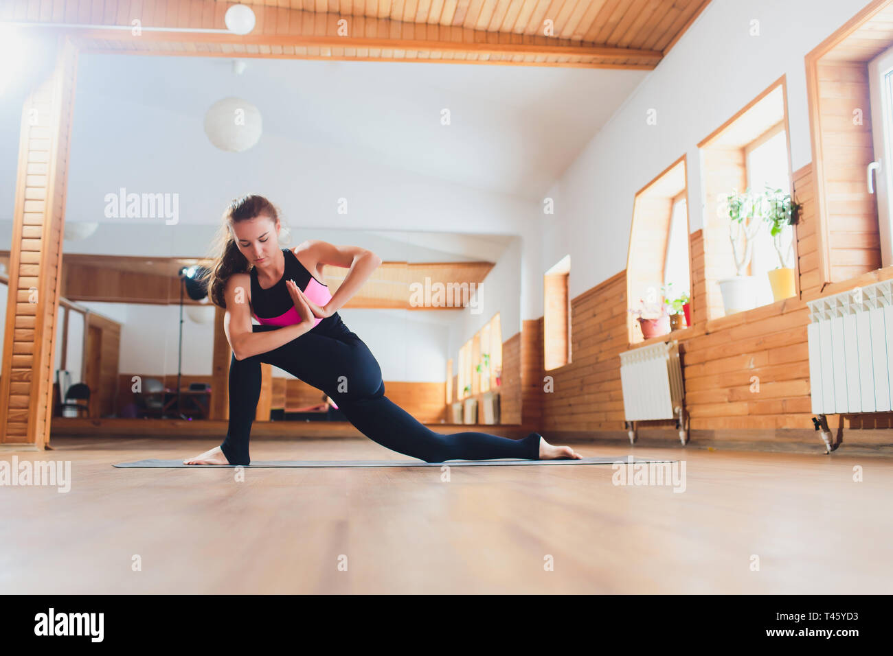 Young attractive yogi woman practicing yoga, standing in Parivrtta ...