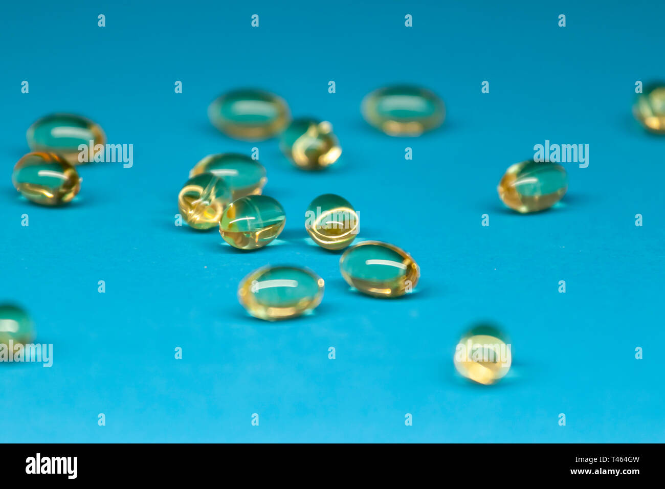 fish oil capsules scattered on blue background Stock Photo - Alamy