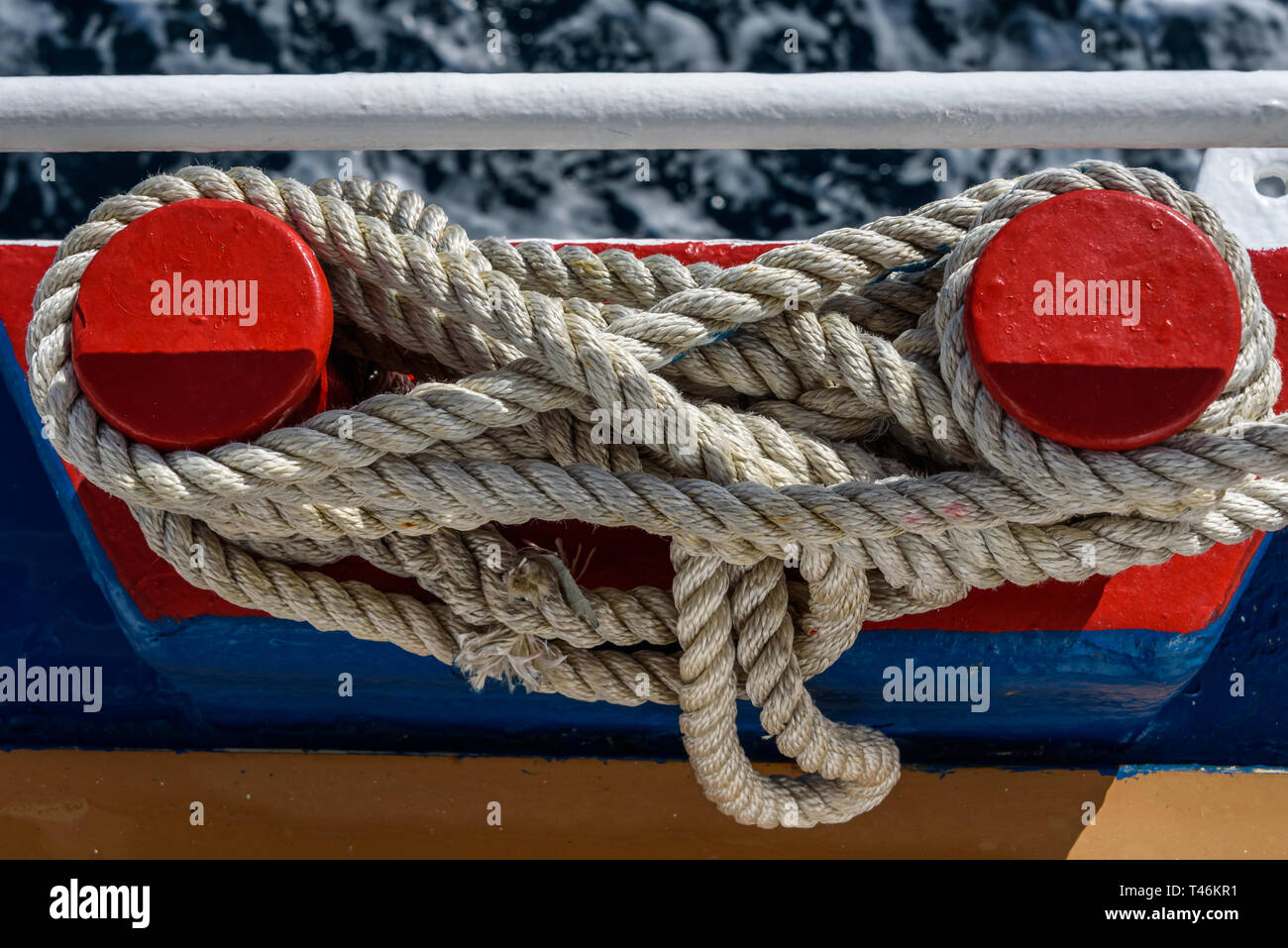 Close up of red double bollard with rope tied around it, ship detail ...