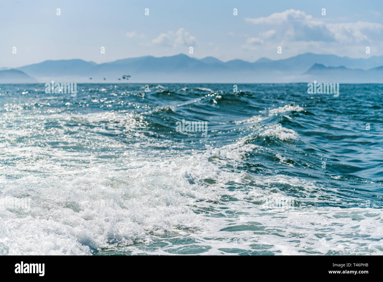 A deep blue sea with island in distance with medium water wave ripple ...