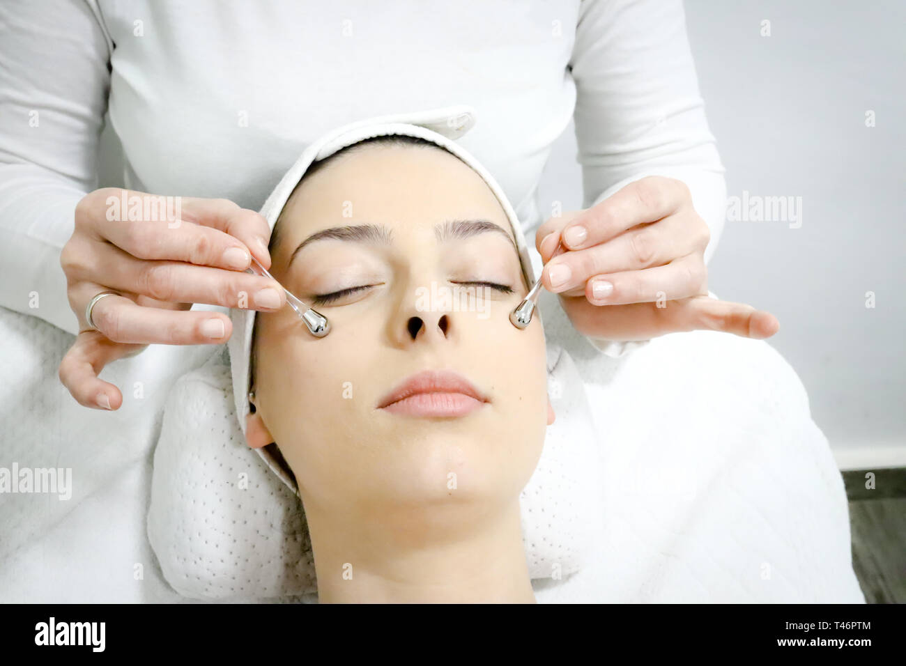 beautician applying collagen treatment for area around the eyes with ...