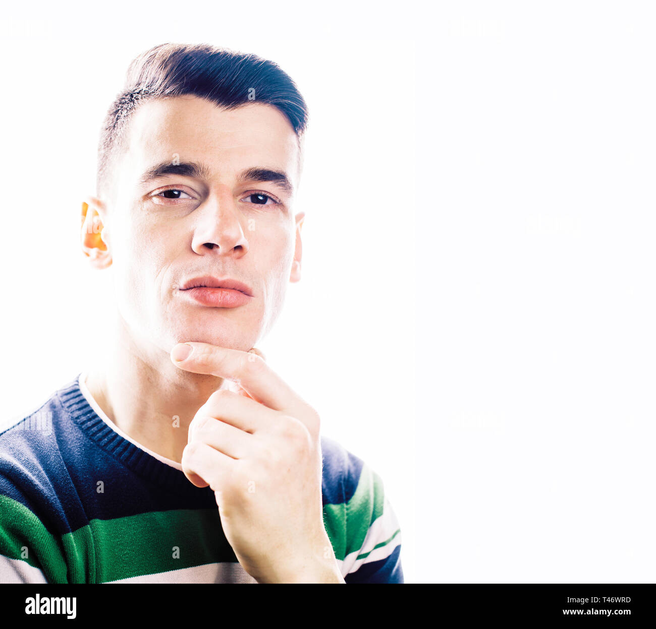 Portrait of a smart serious young man standing against white background ...