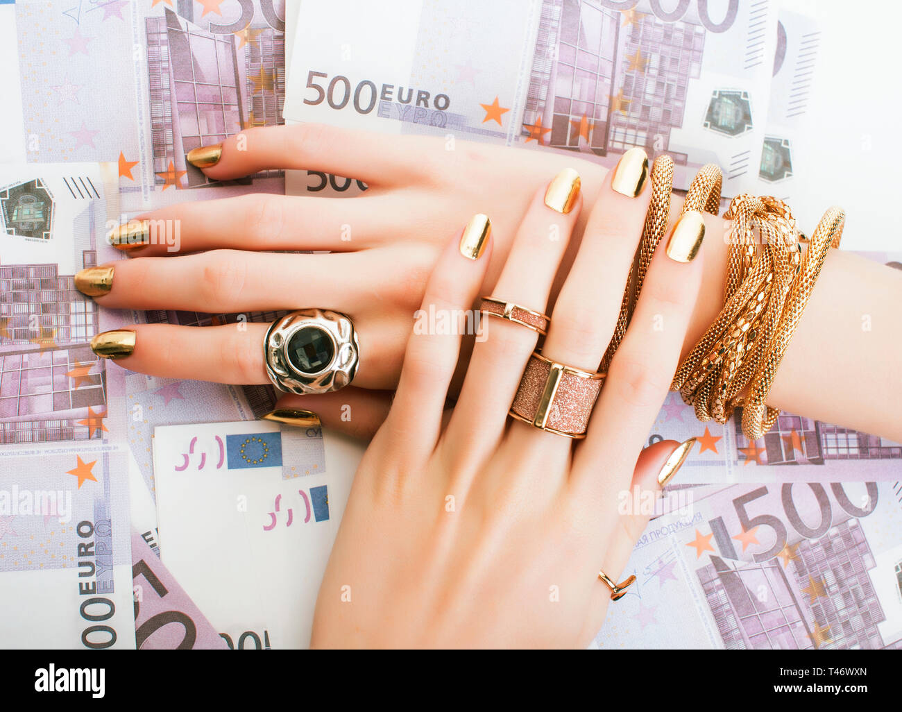 hands of rich woman with golden manicure and many jewelry rings on cash ...