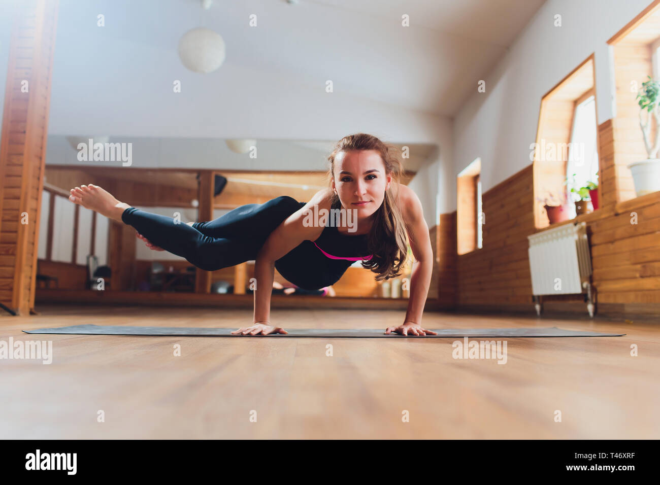 Young attractive yogi woman practicing yoga, standing in Parsva ...