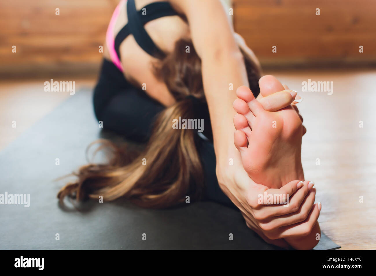 Close-up of a girl doing an asana bending forward with her hands ...