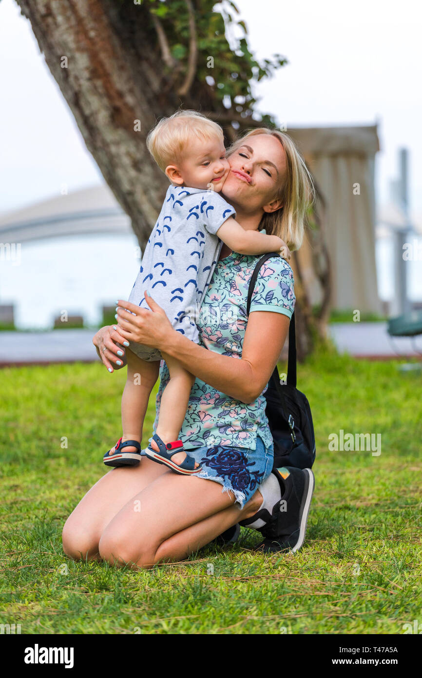 Mom and little boy cuddling on the green grass in the park Stock Photo ...