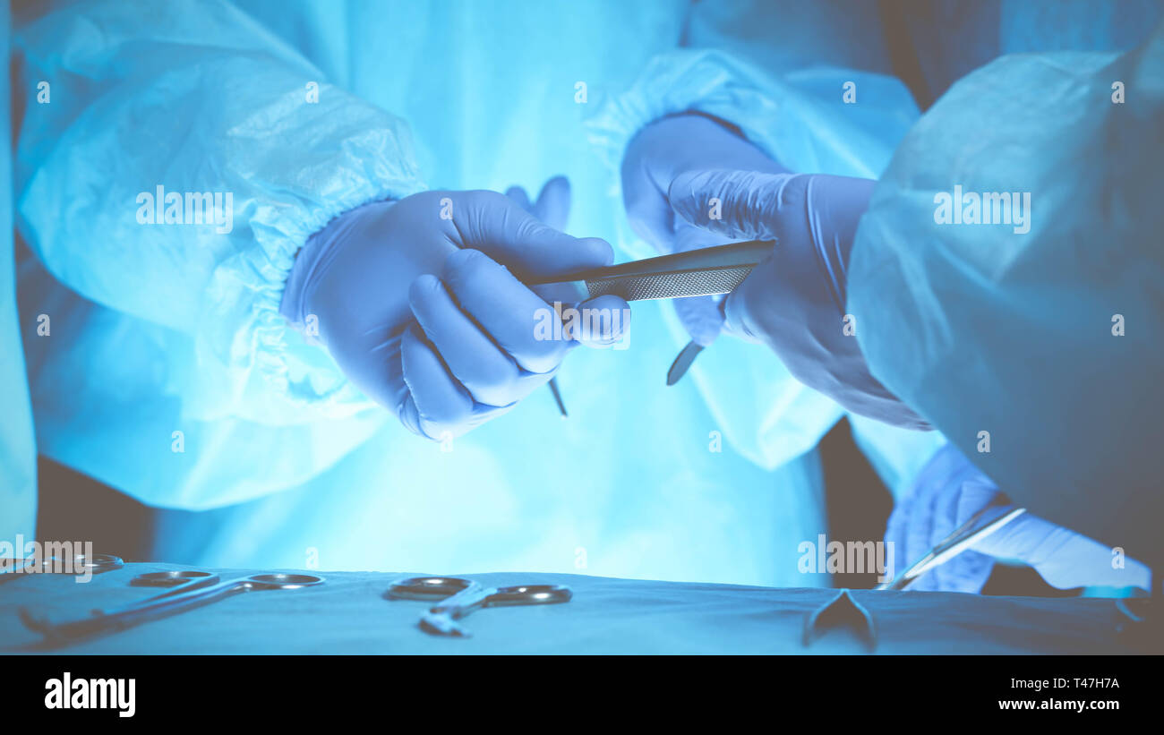 Surgeons hands holding surgical scissors and passing surgical equipment ...