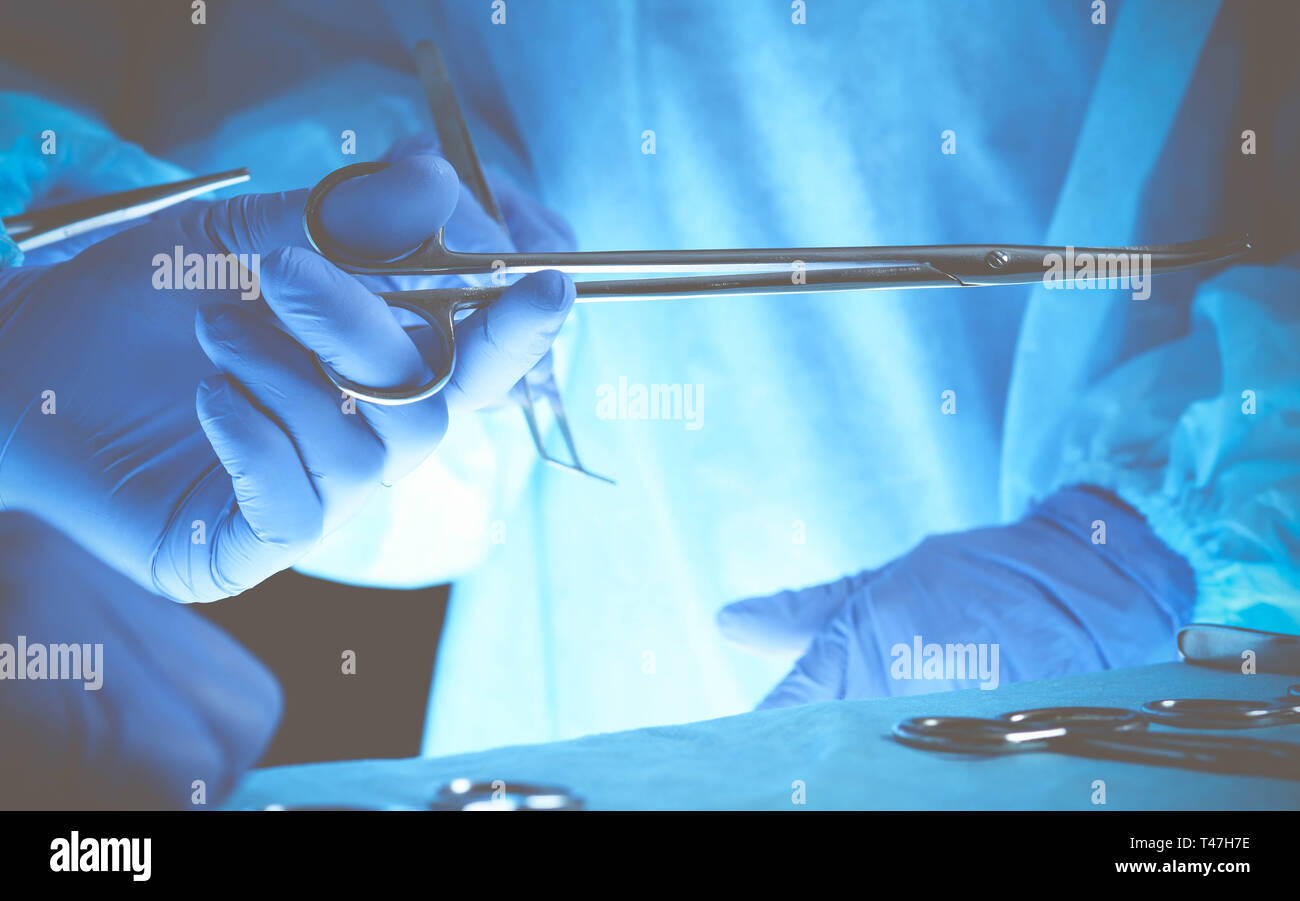 Surgeons hands holding surgical scissors and passing surgical equipment ...