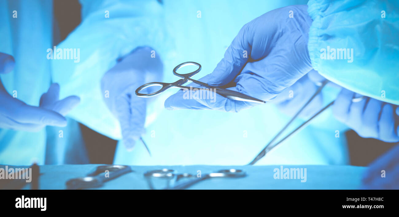 Surgeons hands holding surgical scissors and passing surgical equipment ...