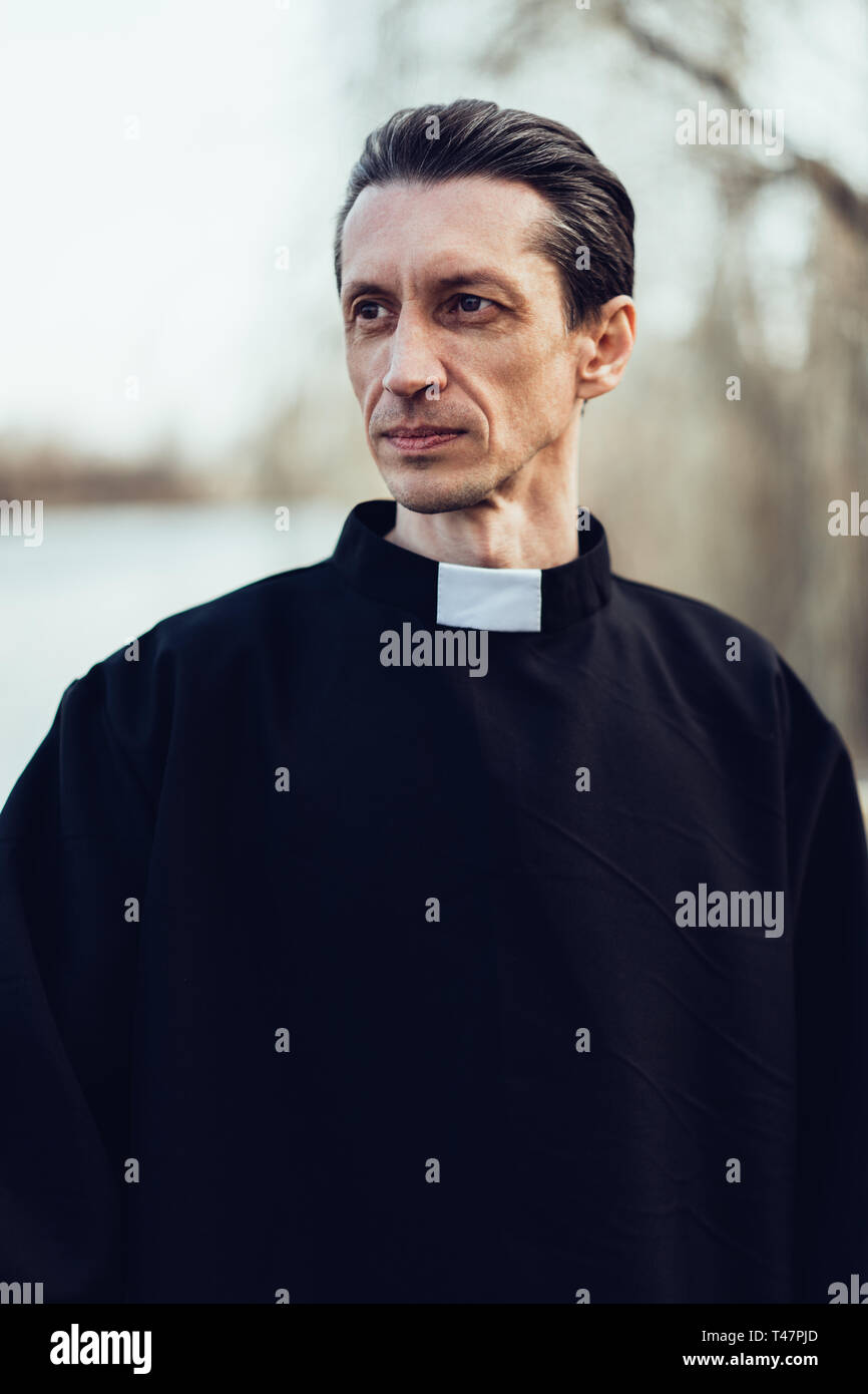 Portrait of handsome catholic priest or pastor with collar Standing ...
