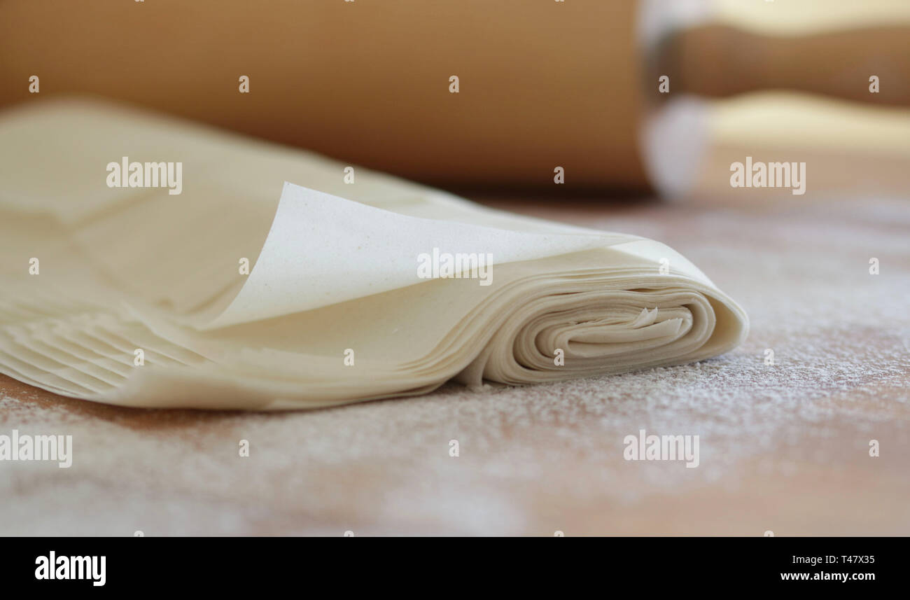 Closeup of homemade fillo pastry isolated on floured table.Rolling pin ...