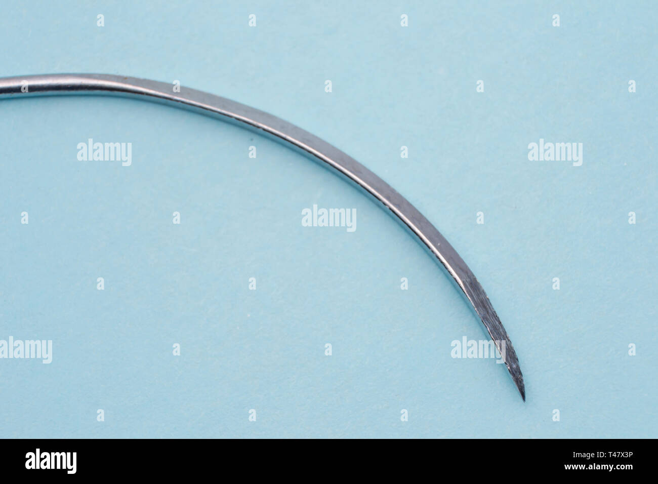 surgical traumatic needle on blue surface Stock Photo - Alamy