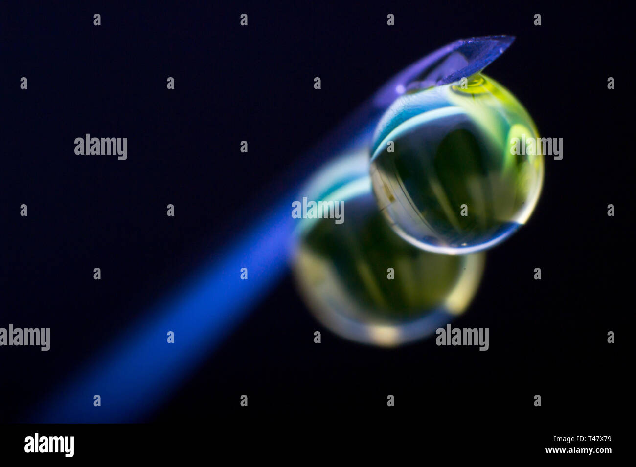 extreme macro view of a hypodermic needle with two drops of drug ...