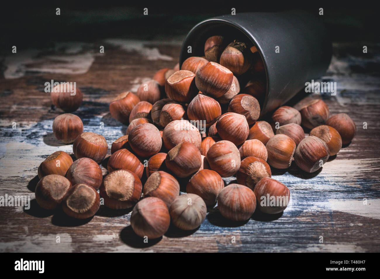 Hazelnut nuts in a dark glass on a dark background. Low key lighting ...