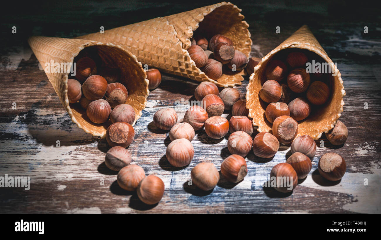 Hazelnut nuts in waffle cones on a dark background. Low key lighting ...