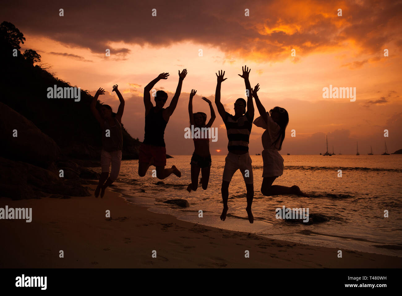 Group of happy people at sea beach at sunset Stock Photo - Alamy