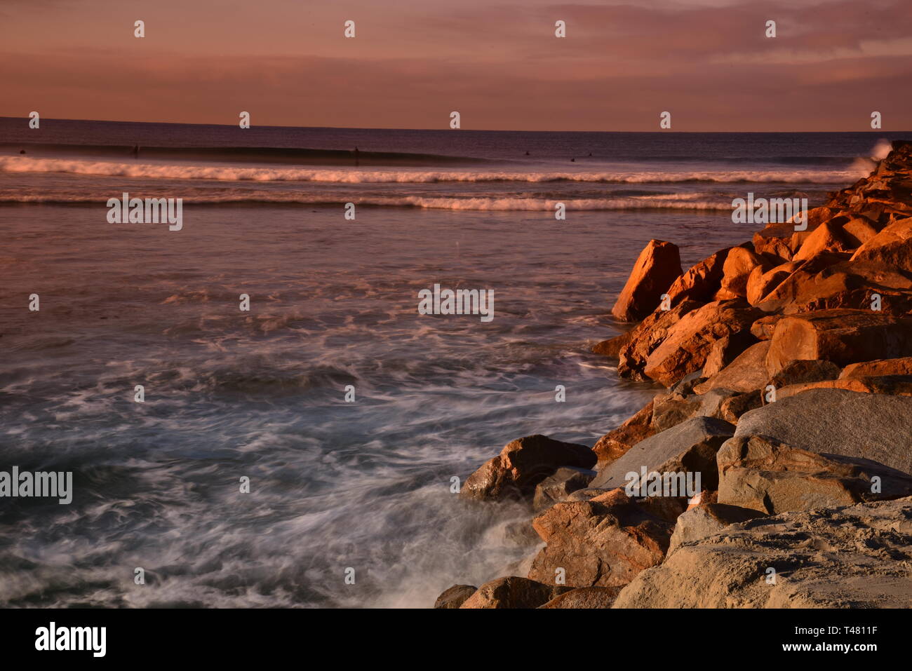 Jetty of boulders and rocks with waved rolling into shore and crashing ...