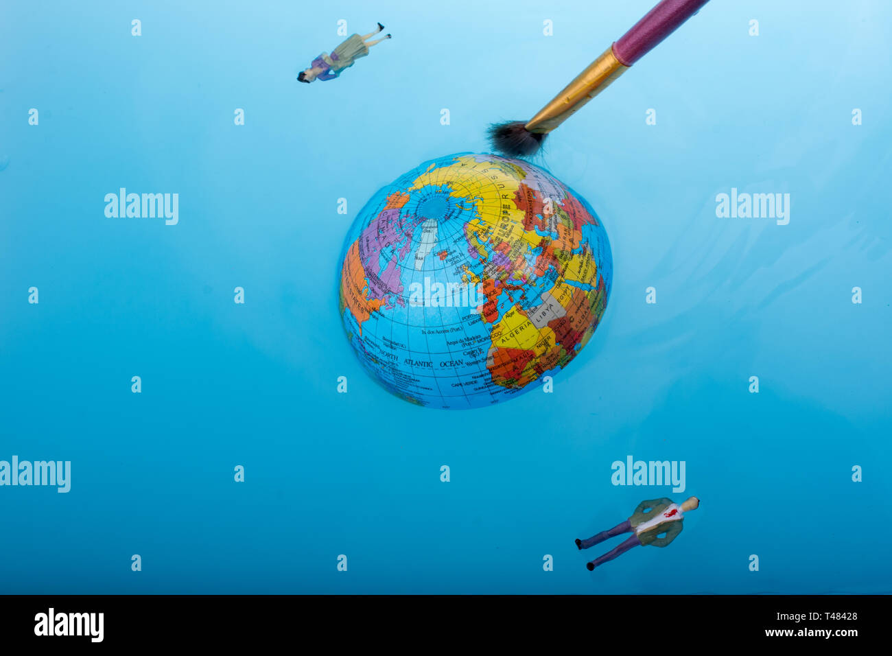 Brush and little globe with floating figurines around in water Stock ...