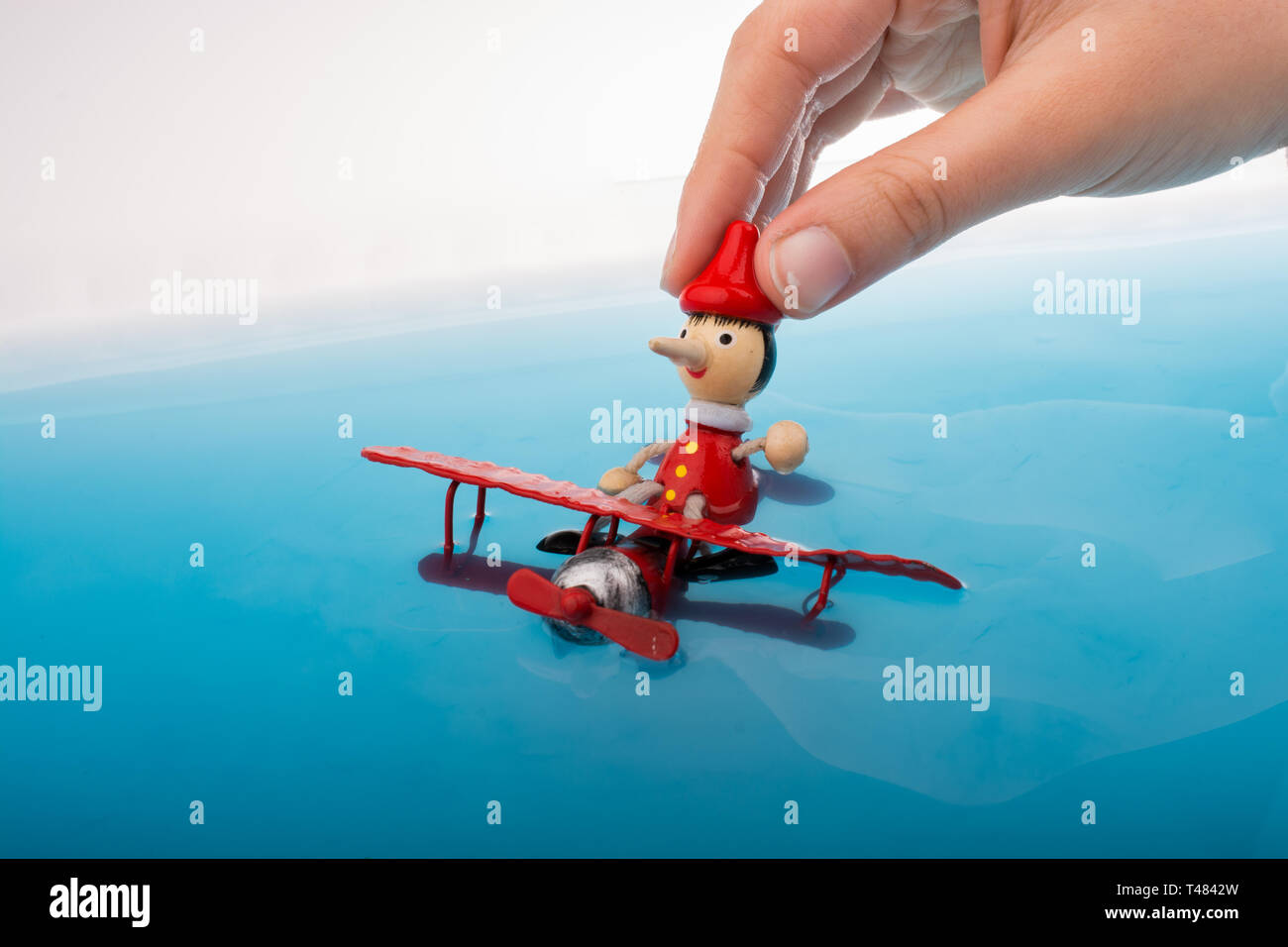 Hand holding Pinocchio on a model airplane in water Stock Photo - Alamy