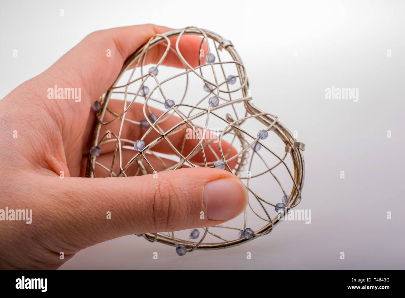 Hand holding heart shaped cage on a white background Stock Photo - Alamy
