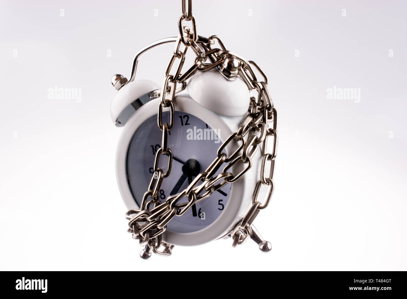 White color alarm clock in chain on a white background Stock Photo - Alamy