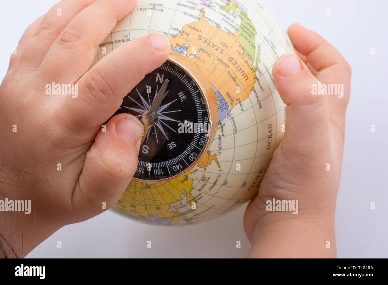 Hand holding a compass and a globe on white background Stock Photo - Alamy