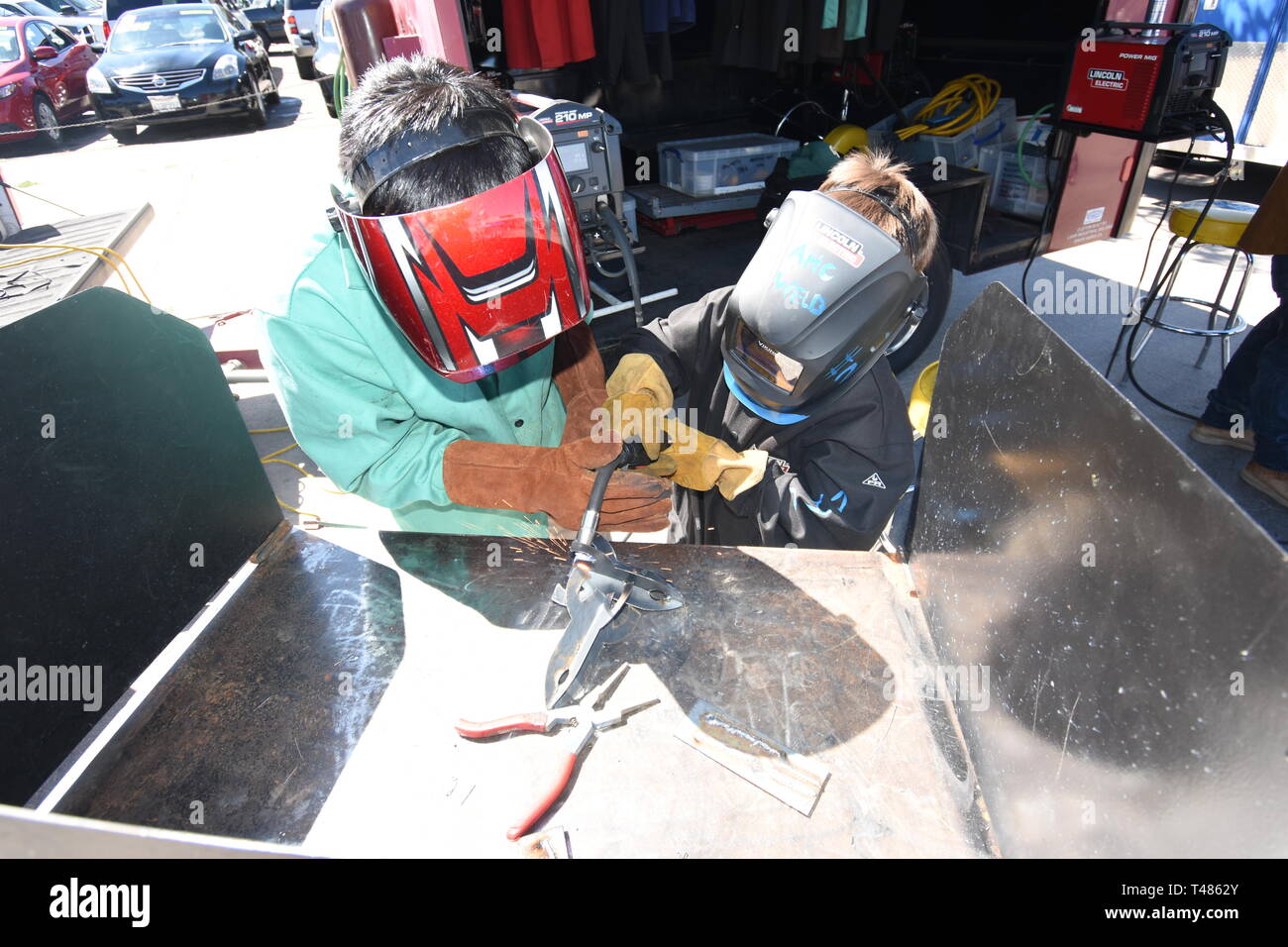 High school teacher and public mentor showing young boy how to weld at ...