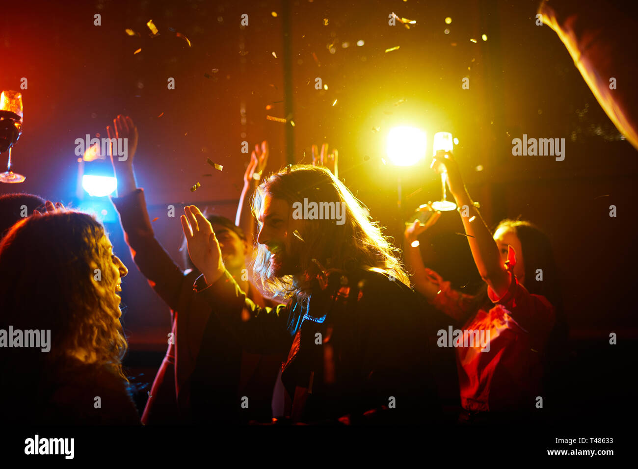Excited people dancing under confetti Stock Photo - Alamy