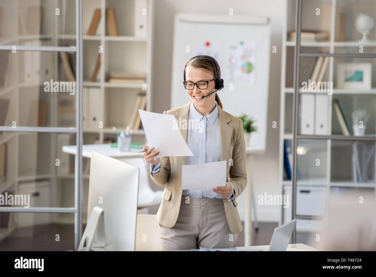 Lady examining papers while talking to customer Stock Photo - Alamy