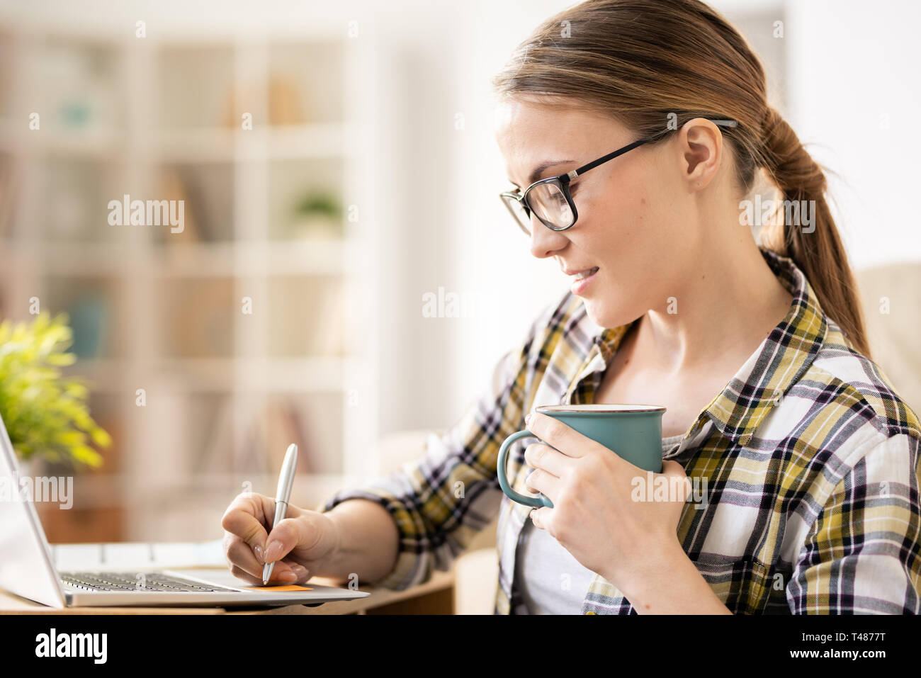 Busy woman writing on stick note Stock Photo - Alamy