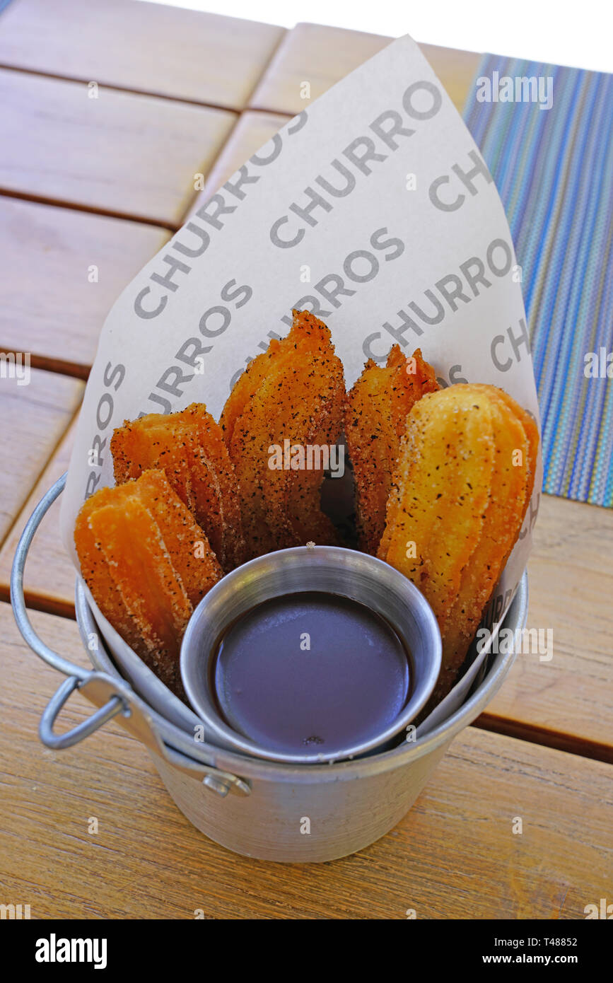 Bucket of fried churros fritters and chocolate sauce Stock Photo - Alamy