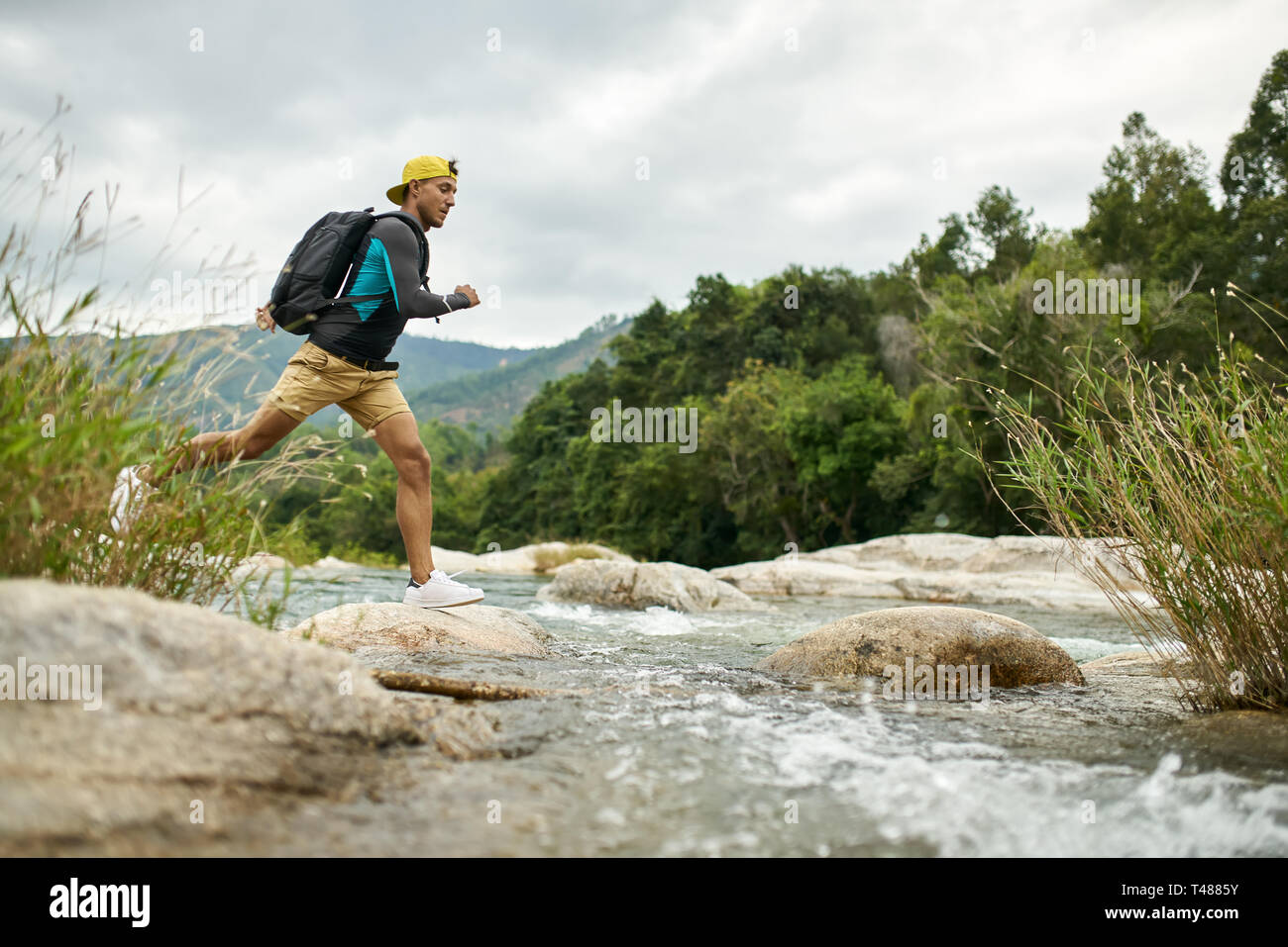 Traveler running through shallow rocky river on nature background Stock ...