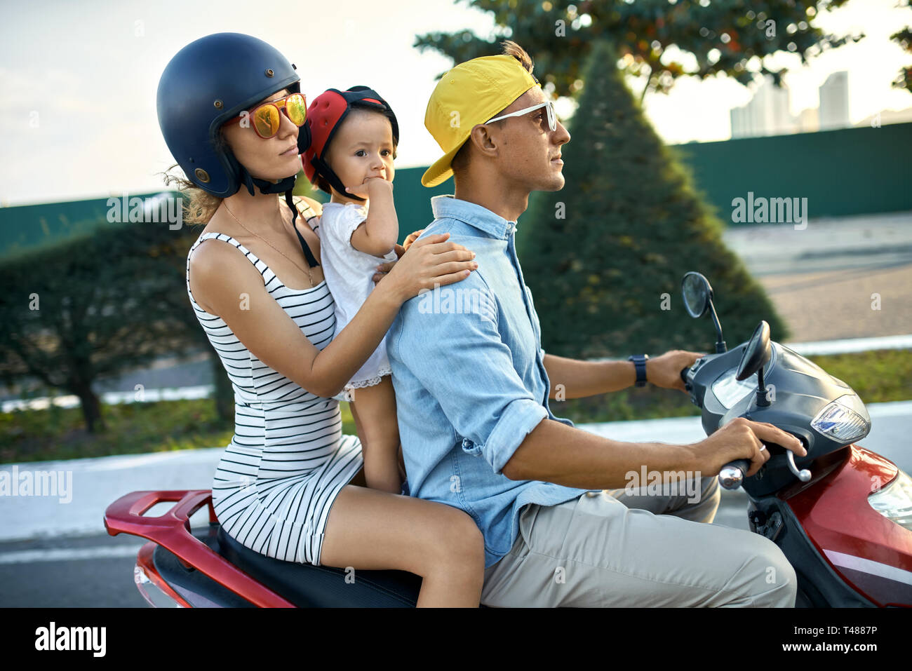 Parents with their child riding motorcycle on sunny city street Stock ...