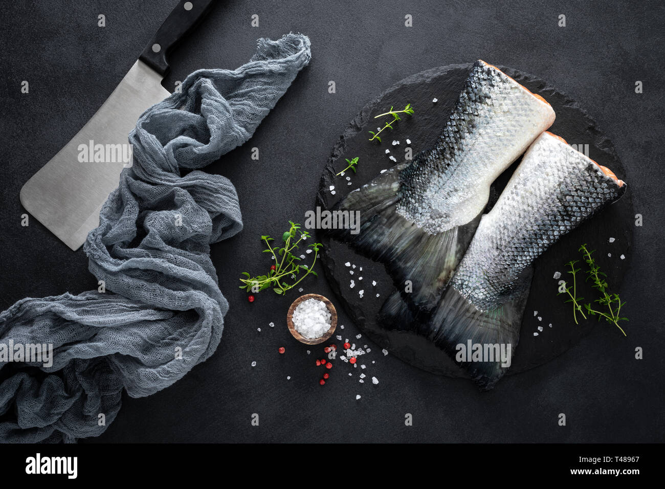 Raw salmon fishtails with ingredients for cooking on black background ...