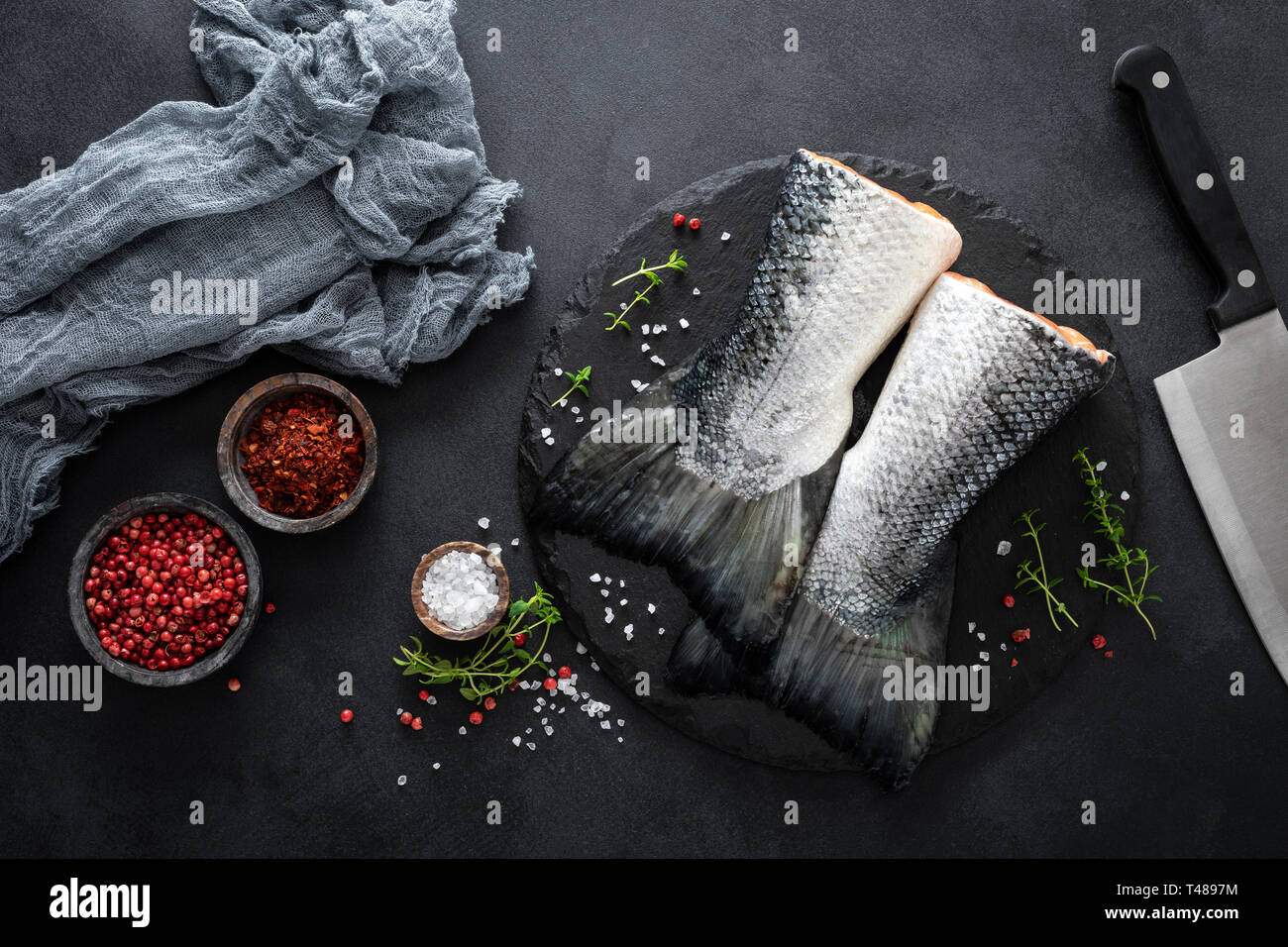 Raw salmon fishtails with ingredients for cooking on black background ...