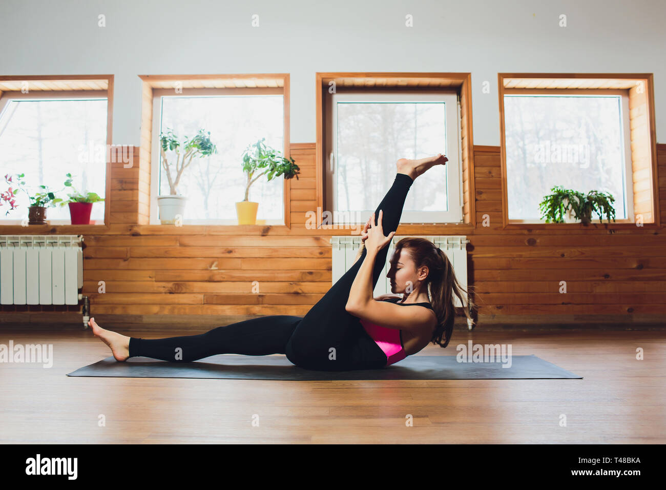 Young yogi sporty woman working out, warming up using yogic belt, lying ...