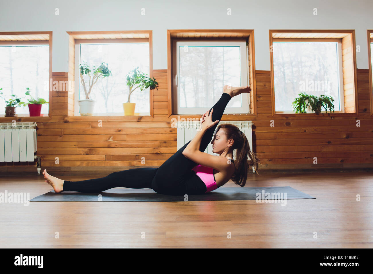 Young yogi sporty woman working out, warming up using yogic belt, lying ...