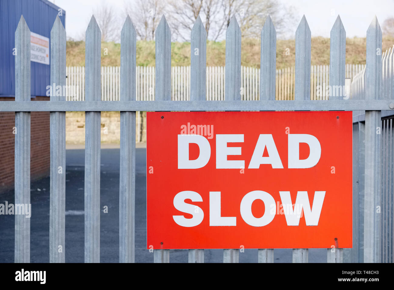 Dead slow road safety sign on industrial business park fence Stock ...