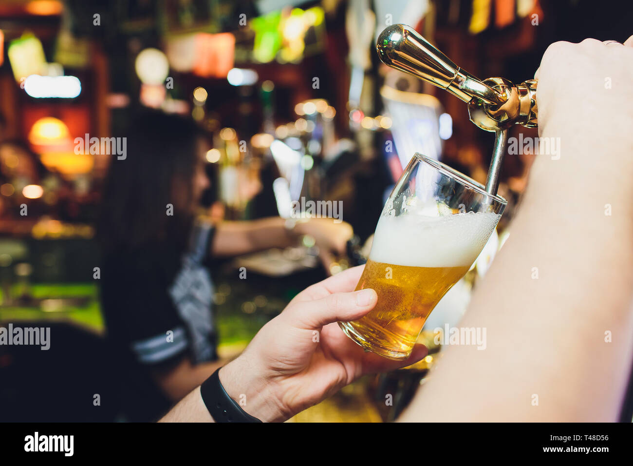 We meet oktoberfest. Hand of bartender pouring a large lager beer in ...