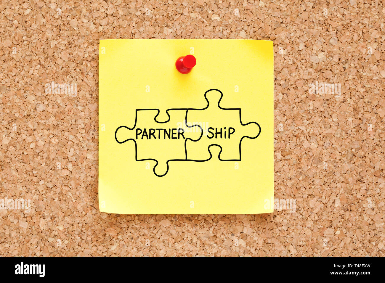 Partnership jigsaw puzzle concept handwritten on yellow sticky note ...