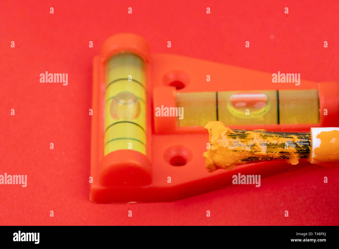 Orange paint on brush with spirit level Stock Photo - Alamy
