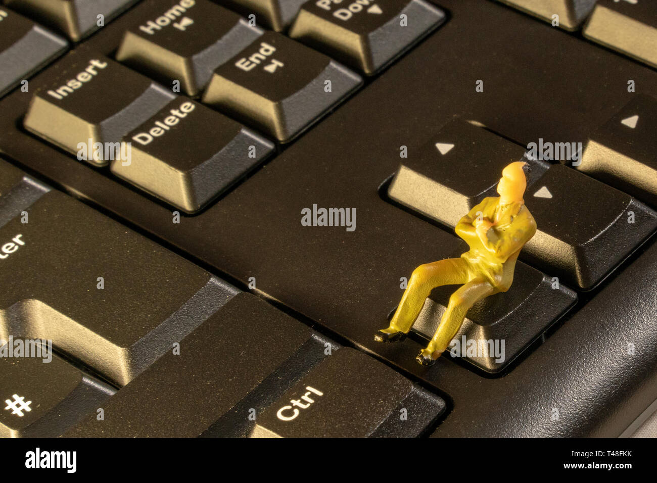 Miniature man sitting on computer keyboard. Computer addiction concept ...