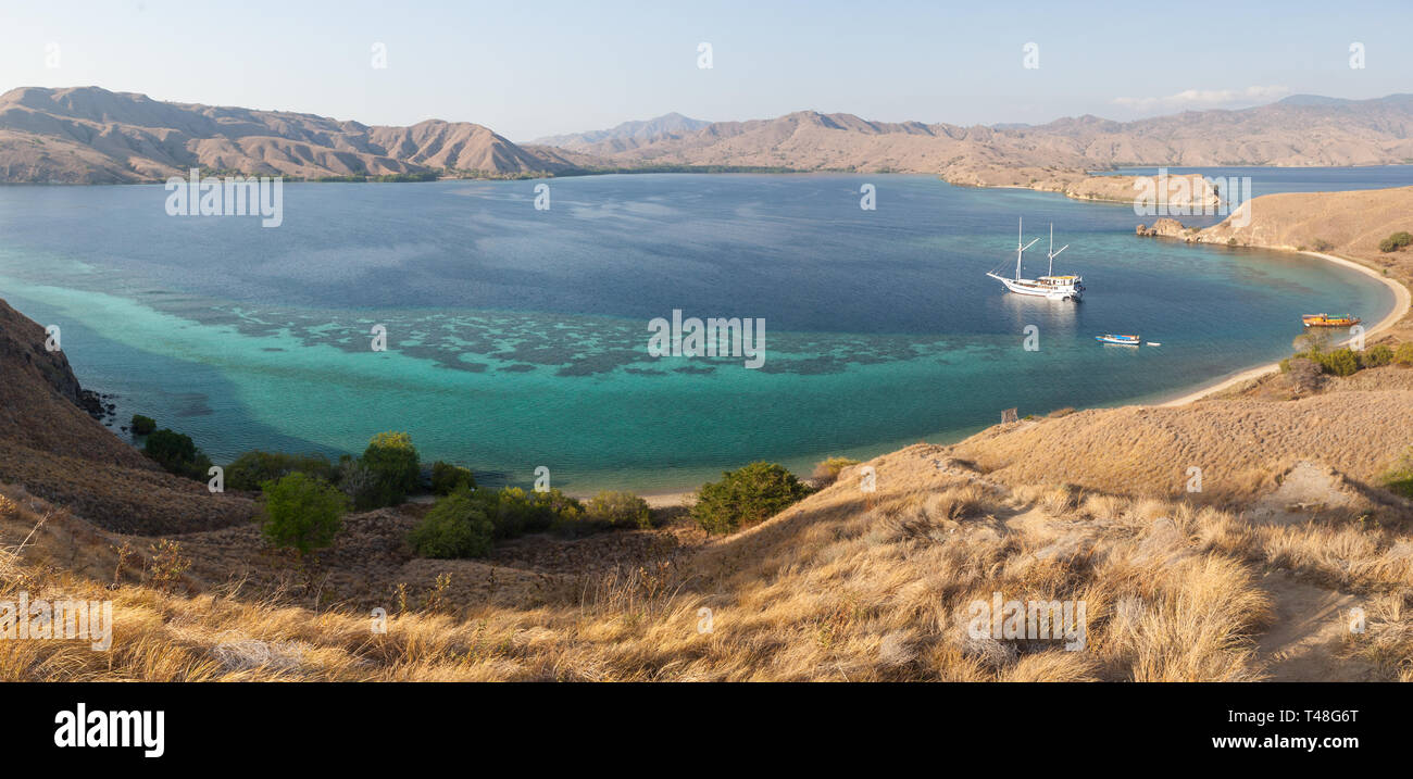 A small ship lies at anchor in a beautiful lagoon in Komodo National ...