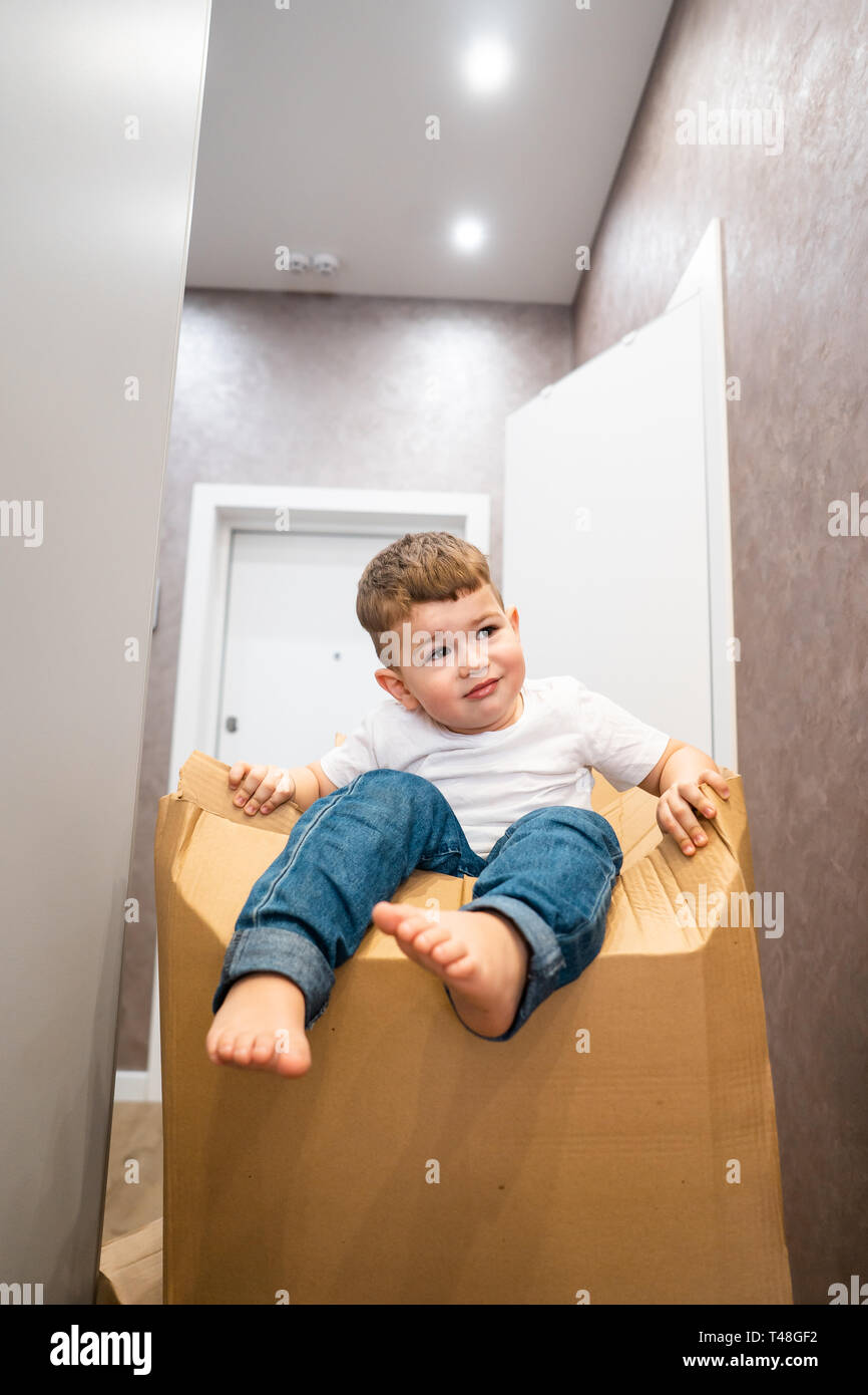 Cute little boy sitting on a cardboard box in the corridor Stock Photo ...